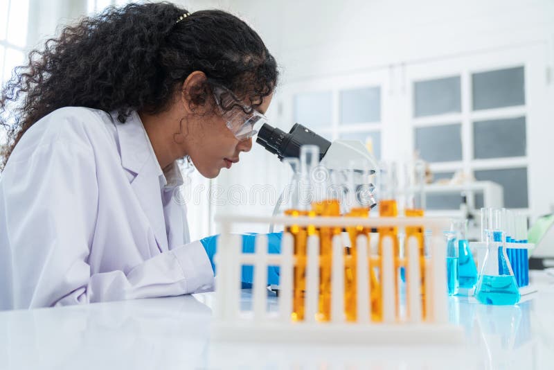 Young Scientist Looking through a Microscope in a Modern Laboratory ...