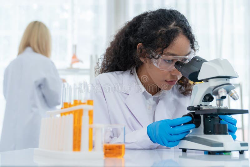 Young Scientist Looking through a Microscope in a Modern Laboratory ...