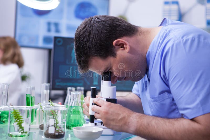Young Scientist Man Doing a Quality Control Looking through Microscope ...