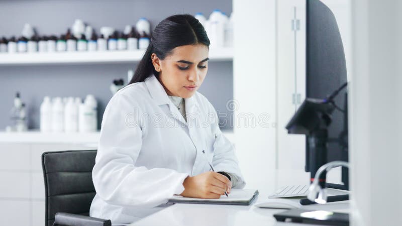 Young Scientist Using a Computer and Microscope in a Lab. Female ...
