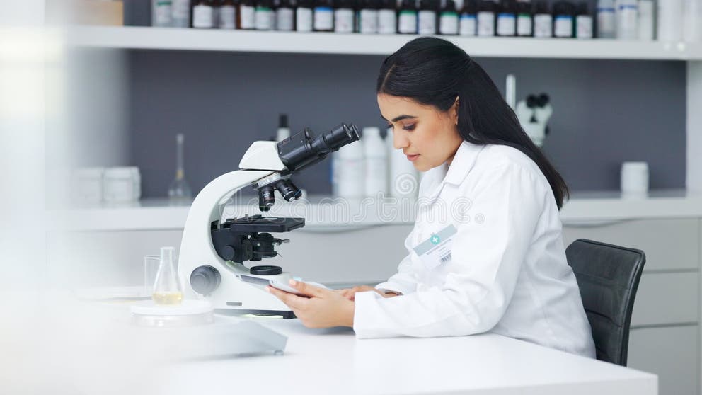 Young Scientist Using a Digital Tablet and Microscope in a Lab. Female ...