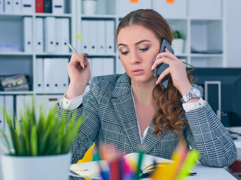 Young Serious Caucasian Businesswoman Sitting At Desk In Office