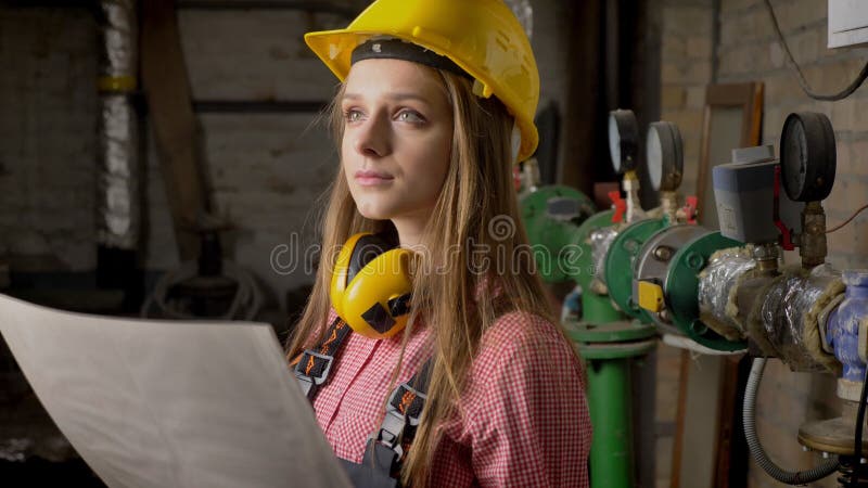 Young Serious Girl Builder is Watching Plan of Building, Watching Above ...