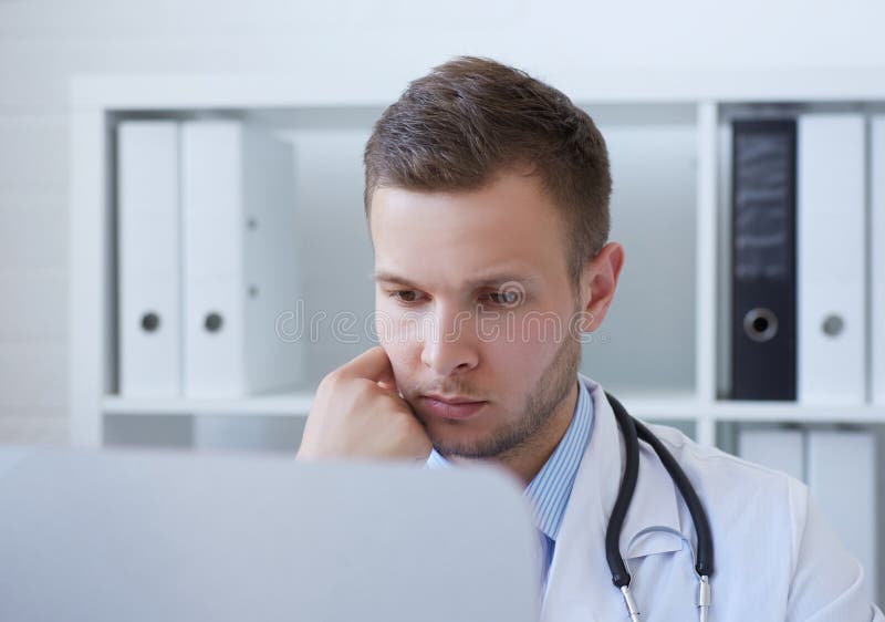 Young Serious Male Doctor Using Computer on Desk in Clinic. Stock Image ...