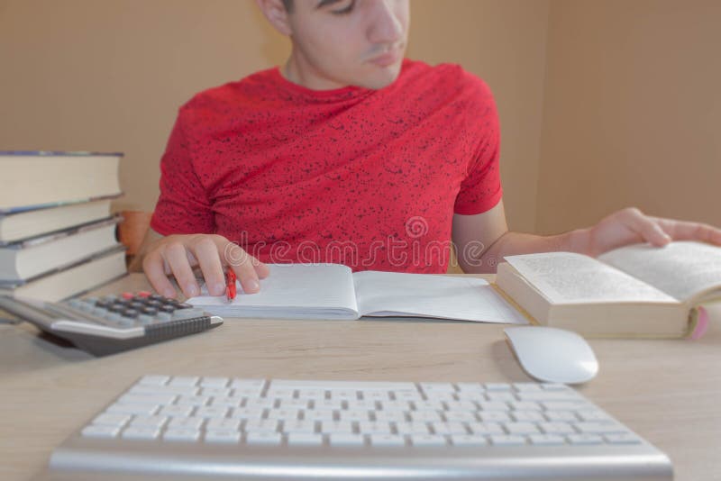 Young Serious Student Reading Book between Books. Man Write in Notebook ...
