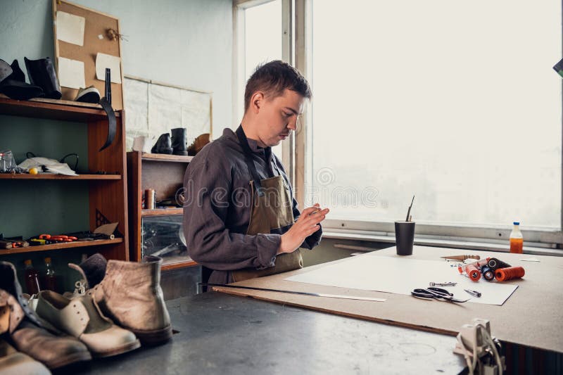 A Young Shoemaker Makes a Drawing for a Pattern for Leather Shoes on a ...
