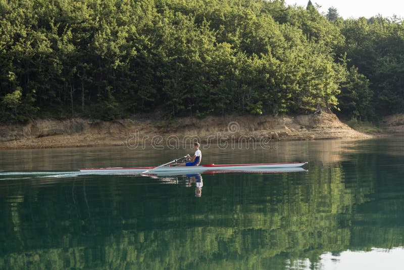 A Young Single Scull Rowing Competitor Paddles on the Tranquil Lake ...
