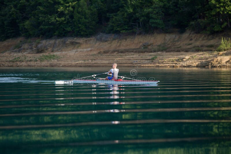 A Young Single Scull Rowing Competitor Paddles on the Tranquil Lake ...