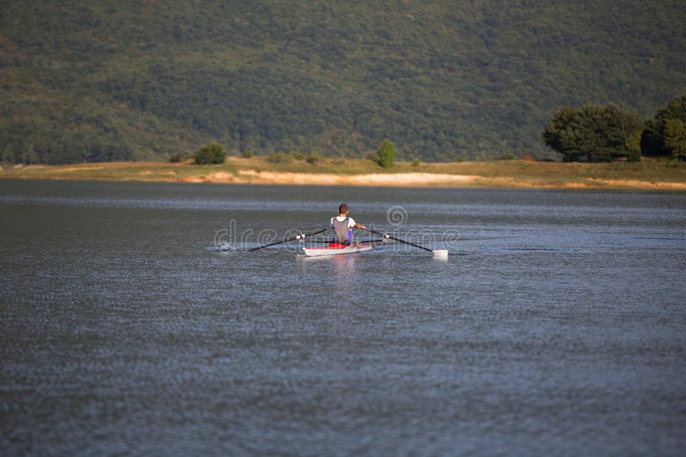 A Young Single Scull Rowing Competitor Paddles on the Tranquil Lake ...