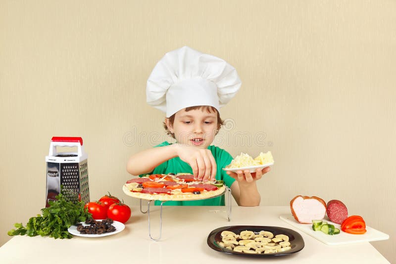 Young Smiling Boy in Chefs Hat Puts a Grated Cheese on Pizza Crust ...