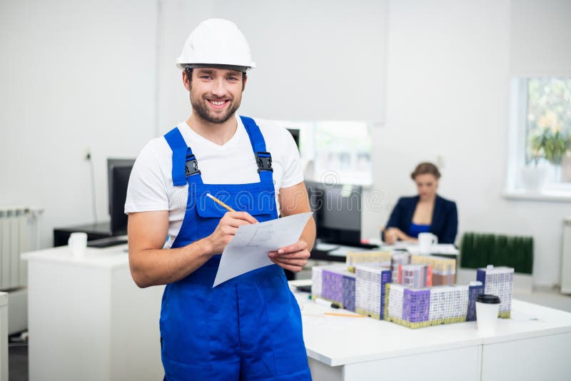 A Young Smiling Construction Worker Taking Notes while in Office Stock ...