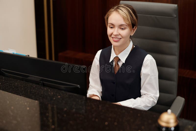 Young Smiling Female Receptionist Entering Data of Hotel Guests in ...