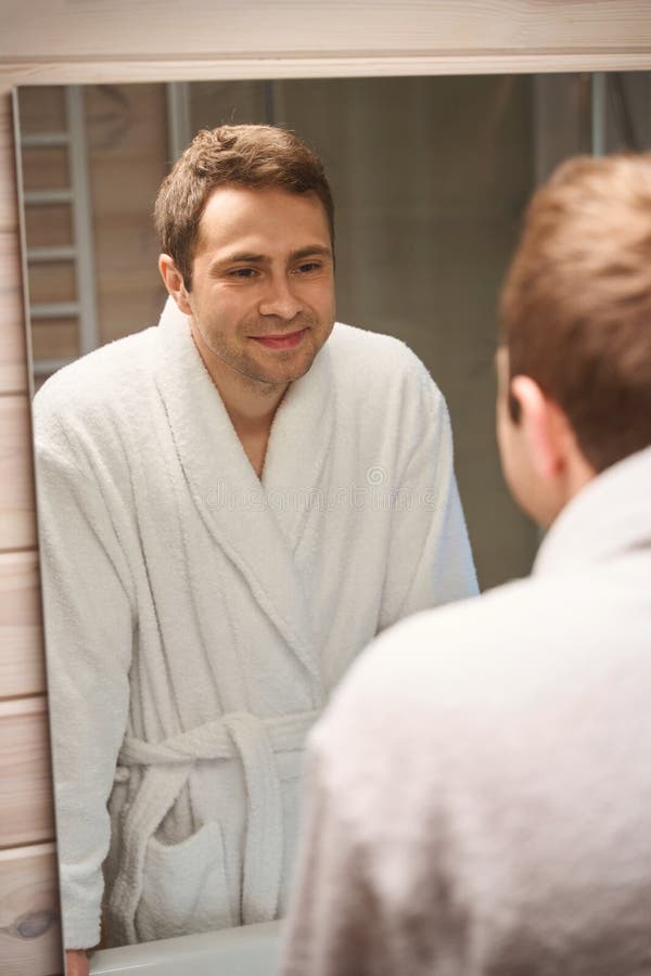 Young Smiling Man Looks at Himself in the Bathroom Mirror Stock Photo ...