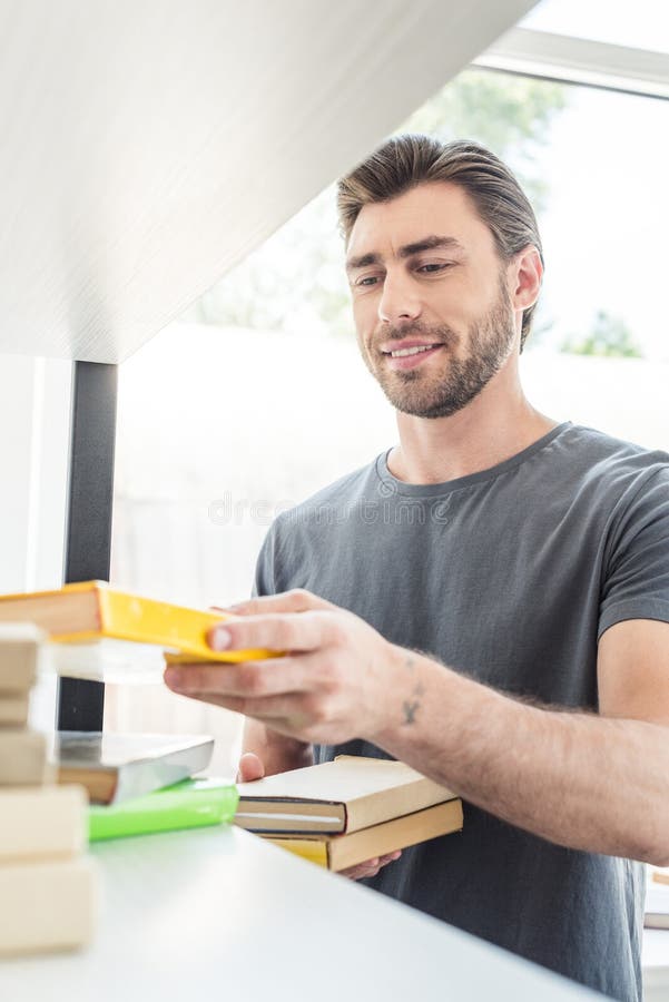 Young Smiling Man Putting Books on Shelves Stock Photo - Image of read ...