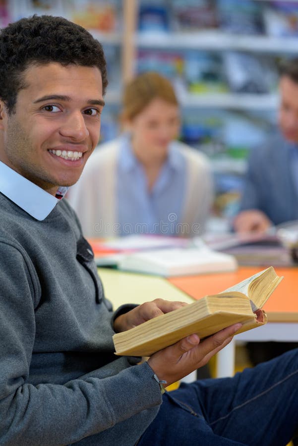 Young Smiling Man Reading Book in Library Stock Image - Image of ...