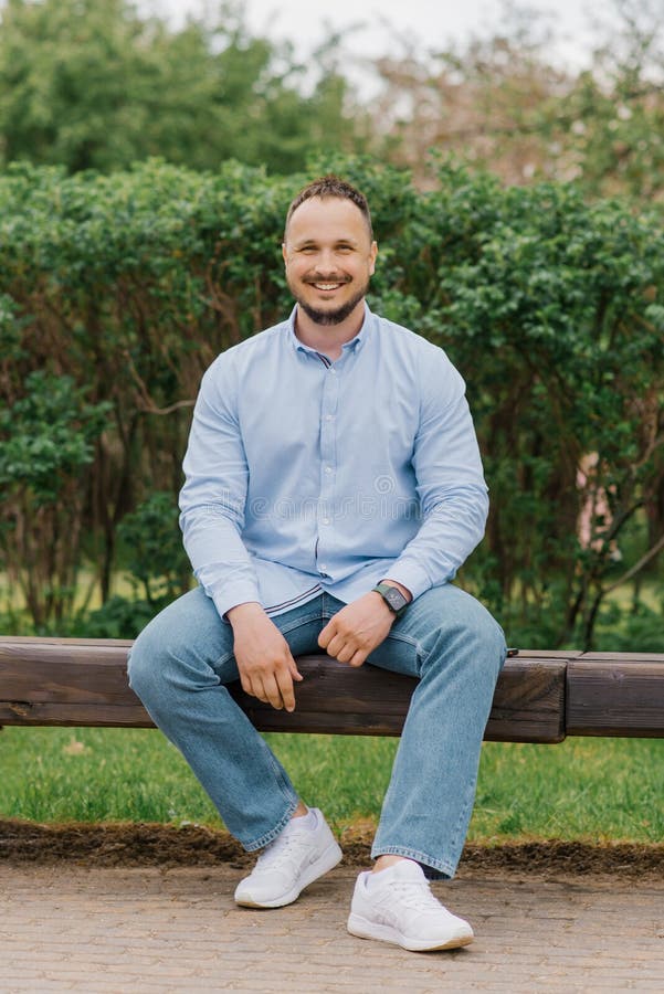 Young Smiling Man is Sitting on a Park Bench. the Concept of Rest and ...