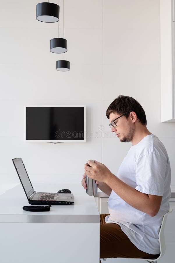 Young Smiling Man Working with Laptop from Home, Drinking Water Stock ...