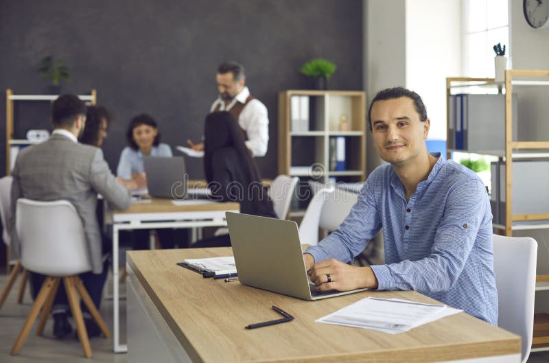 Young Smiling Office Worker is Typing on a Laptop, Working on a Project ...