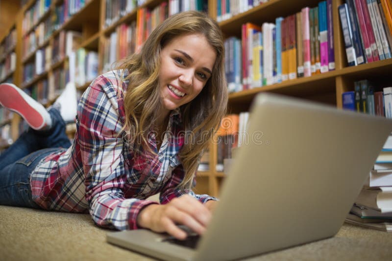 Young Smiling Student Lying on Library Floor Using Laptop Stock Image ...