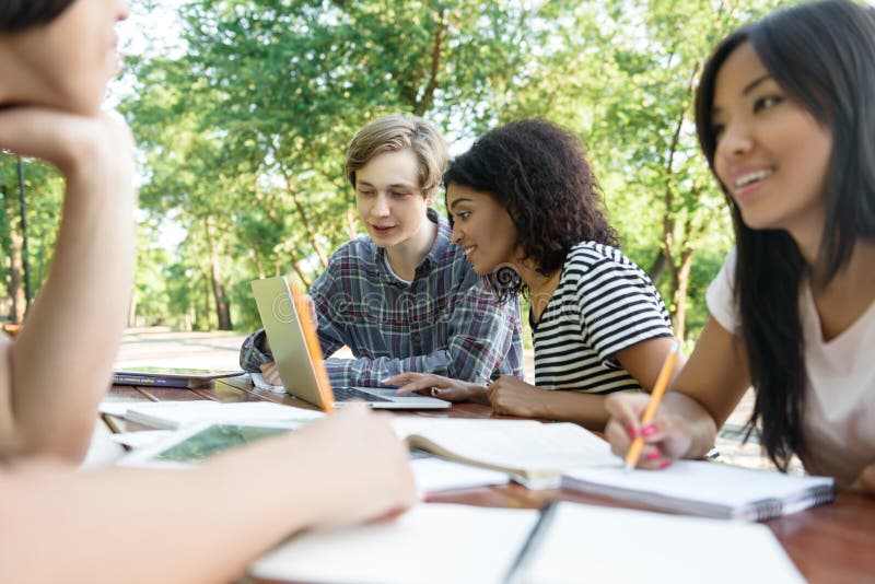 Young Smiling Students Sitting and Studying Outdoors Stock Image ...