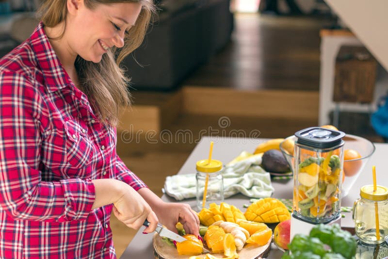 Young Smiling Woman Making Smoothie With Fresh Greens In The Blender In