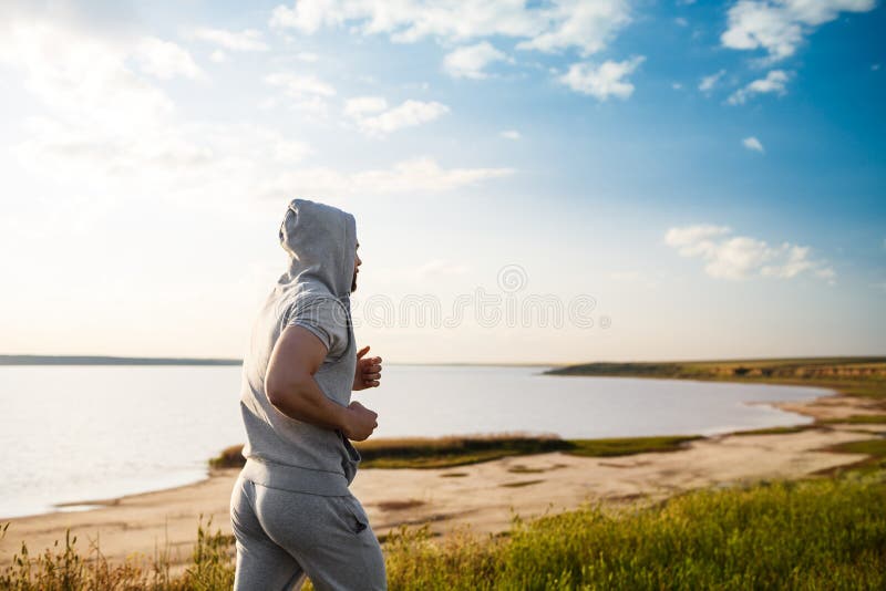 Young Sportive Man Jogging in Field at Sunrise. Stock Image - Image of ...