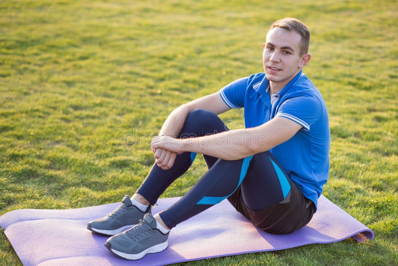 Young Sportive Man Sitting on Training Mat in Morning Field Outdoors ...