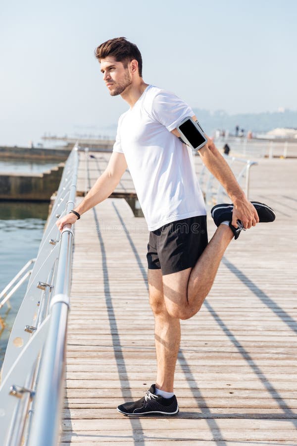 Young Sportsman Stretching Legs during Workout on Pier Stock Photo ...