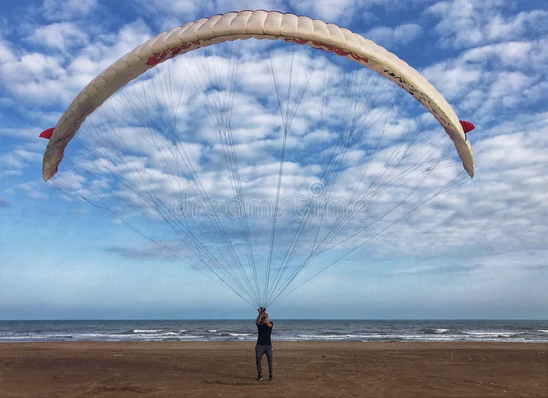 Young Standing on a Beach with a White Parachute in His Hands Against ...