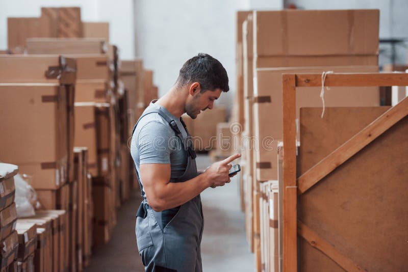Young Storage Worker in Uniform Stands and Uses His Phone Stock Image ...