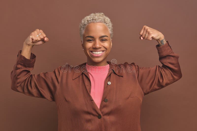 Young Strong African American Woman Raises Arms To Show Muscles Stands