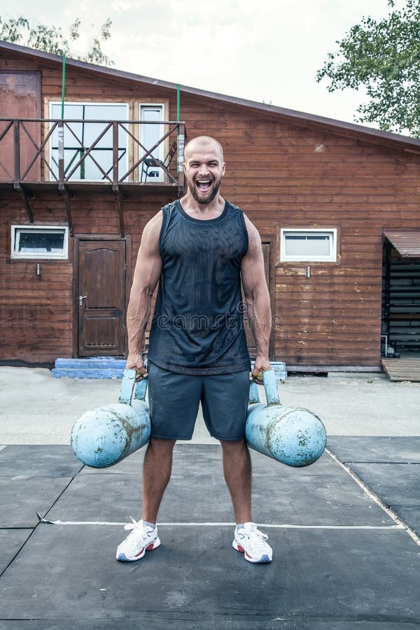 Young Strong Man Bodybuilder with Big Barrels in Hands Screaming To the ...