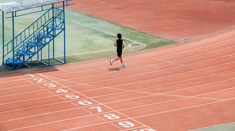Young Student is Doing Long-distance Running Exercises on the Red Track ...