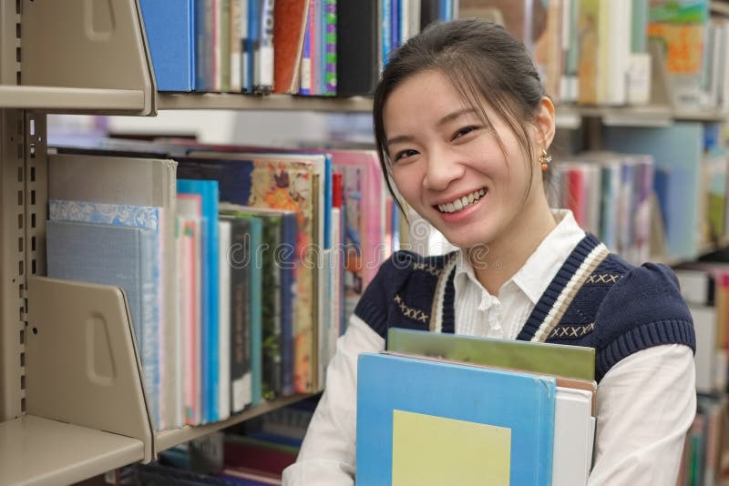 Young Student Holding Books Near Bookshelf Stock Photo - Image of ...