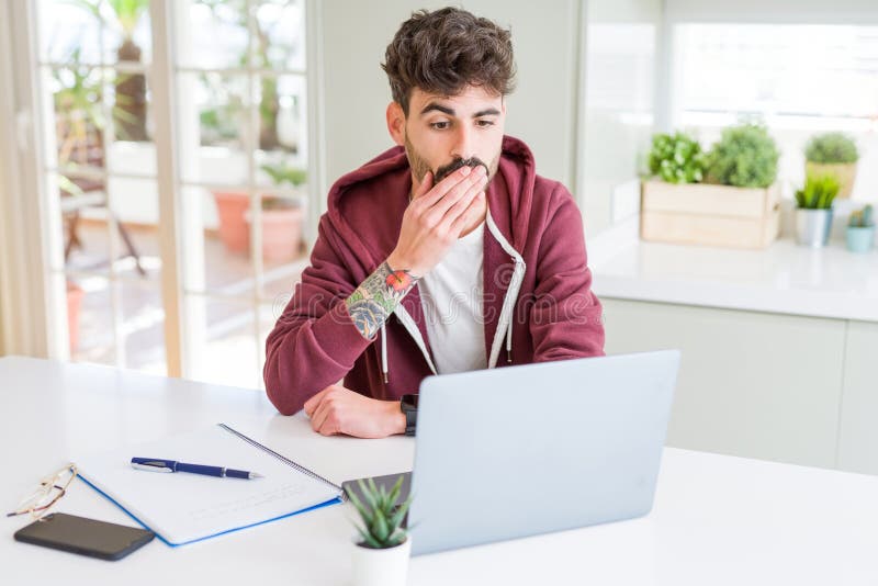 Young Student Man Using Computer Laptop and Notebook Cover Mouth with ...