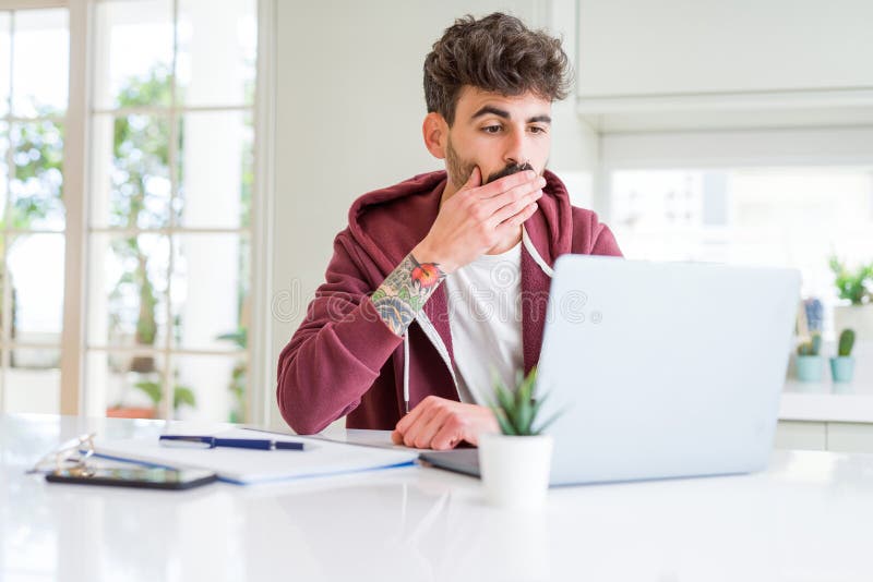 Young Student Man Using Computer Laptop and Notebook Cover Mouth with ...