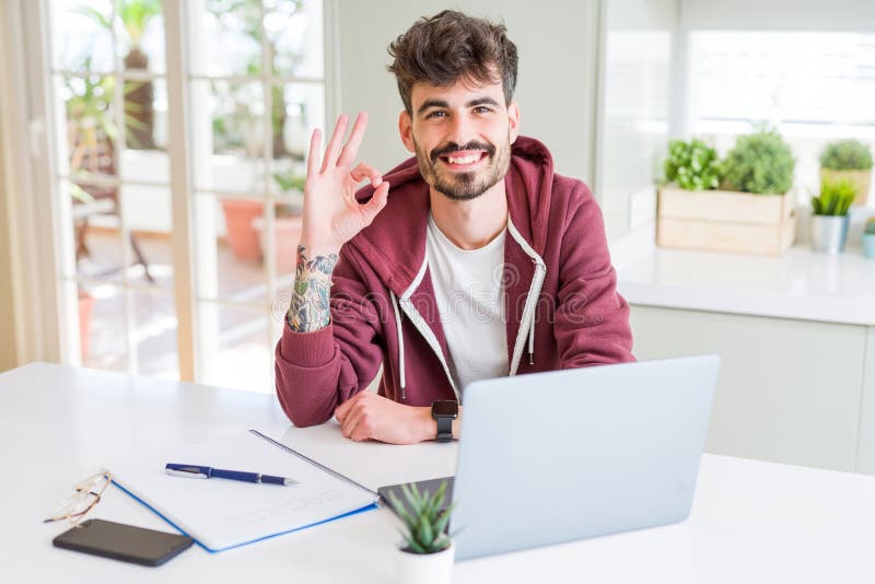 Young Student Man Using Computer Laptop and Notebook Doing Ok Sign with ...