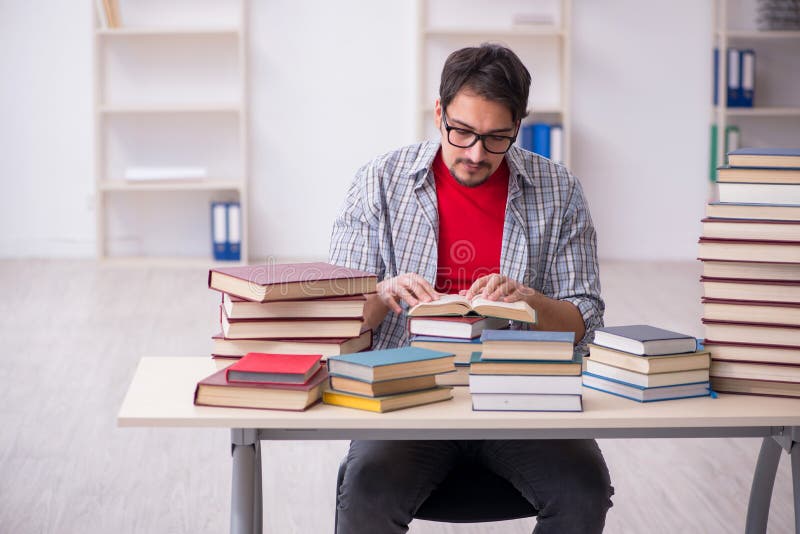 Young Male Student and Too Many Books in the Classroom Stock Photo ...