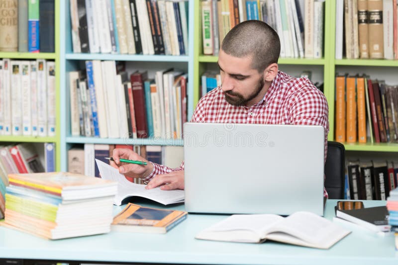 Young Student Using His Laptop in a Library Stock Photo - Image of male ...