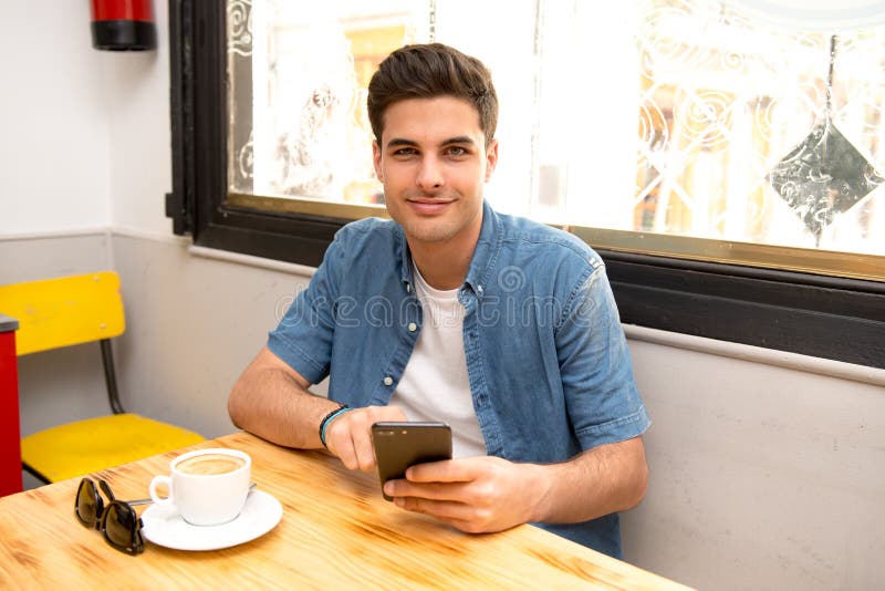 Young Student Using His Smart Phone To Read Text while Having a Coffee ...