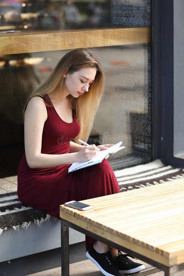 Young Student Writing Down in Notebook at University, Smartphone on ...