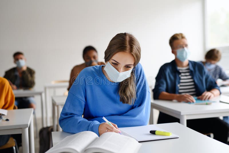Young Students with Face Masks at Desks at College or University ...