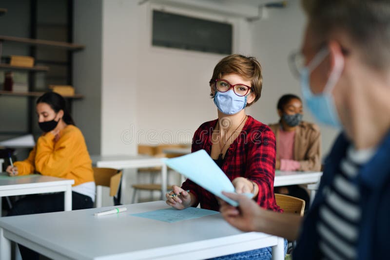 Young Students with Face Masks at Desks at College or University ...