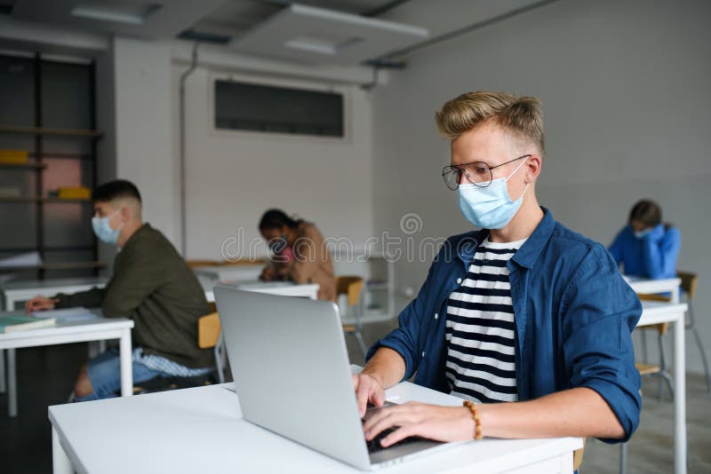 Young Students with Face Masks at Desks at College or University ...