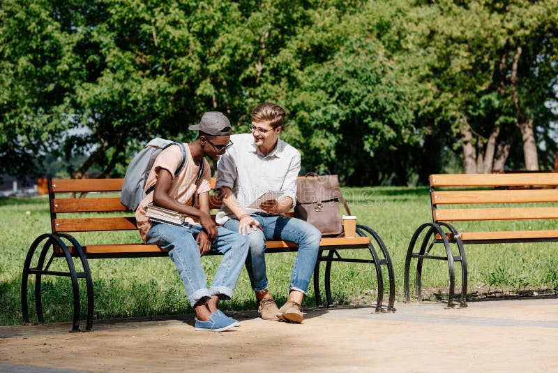 Young Students Sitting on Bench and Studying in Park Together Stock ...