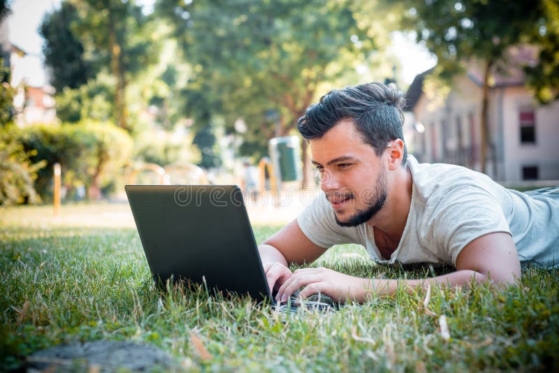 Young Stylish Man Using Notebook Stock Image - Image of outdoor, lying ...
