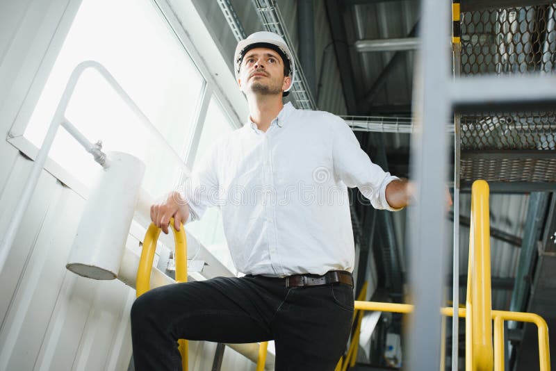 A Young Successful Engineer with a Drawing in His Hands is Standing in ...