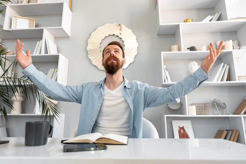 Young Successful Man Sitting at the Table Raising His Hands Stock Photo ...