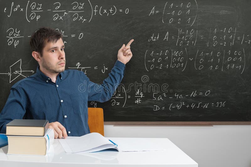 Young Teacher is Pointing on Math Formulas on Blackboard with Finger ...