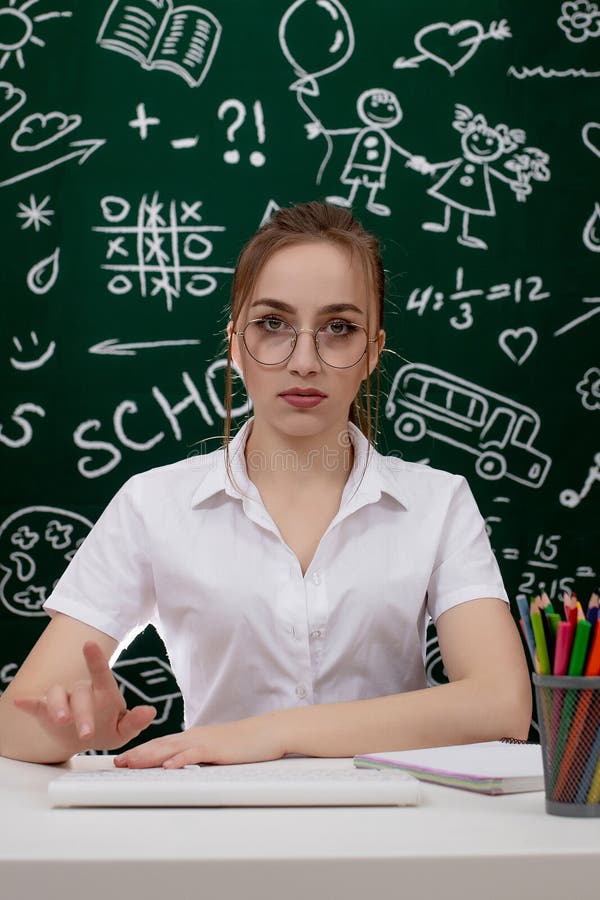 Young Teacher is Sitting Near Blackboard in Classroom Stock Photo ...